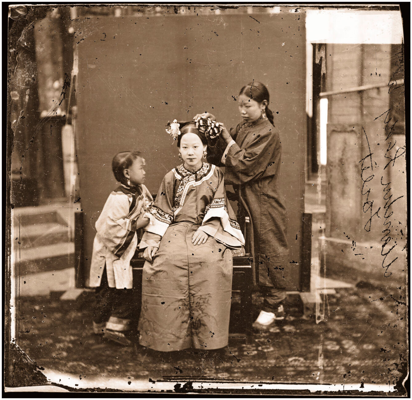 China: a Manchu lady having her hair dressed by her servant girl ...