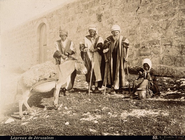 A group of lepers in Jerusalem: three standing men with sticks, a woman ...