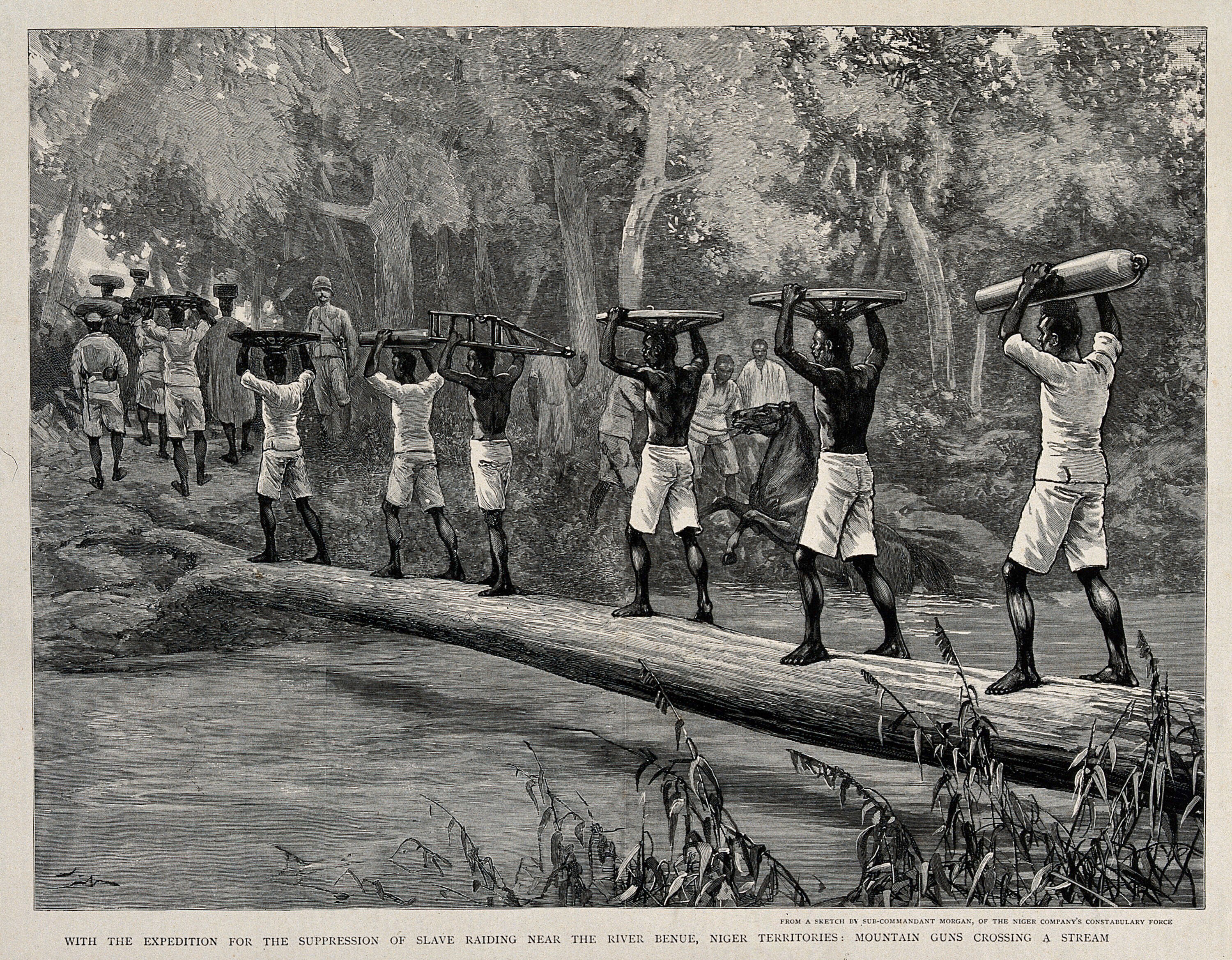 Nigerian porters carrying gun parts across the Benue river in a British ...